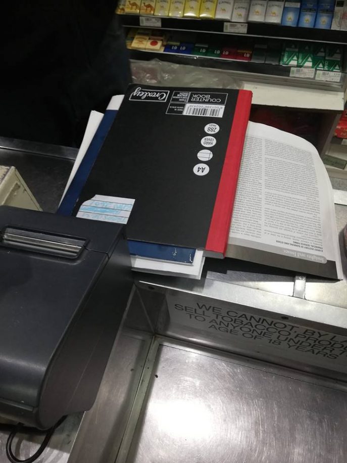 Man working as garage cashier inspires by studying while on shift